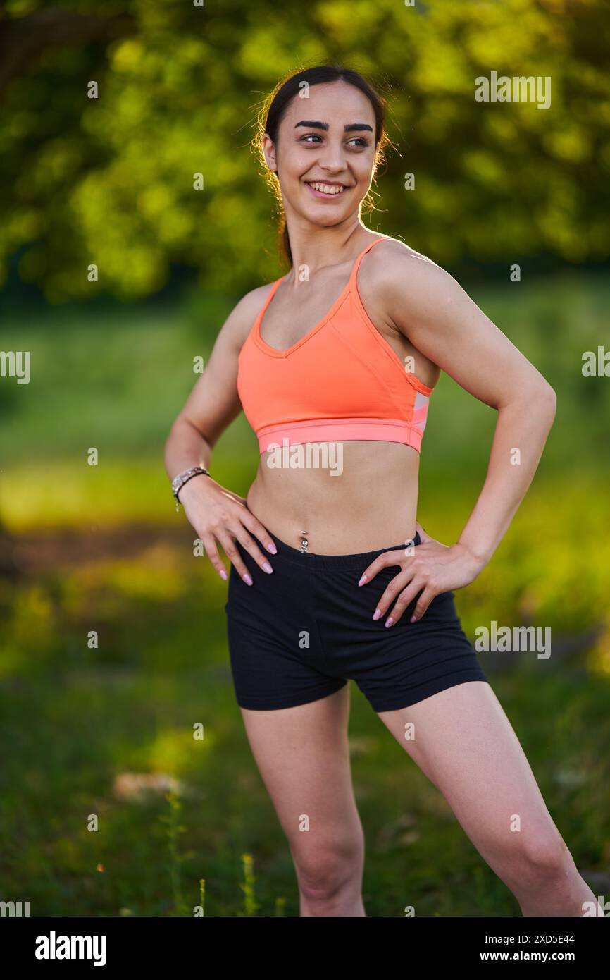 Fitness model posing in varioius postures on a meadow by the forest ...