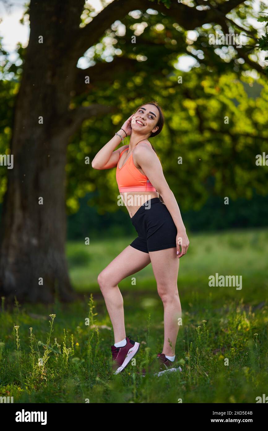 Fitness model posing in varioius postures on a meadow by the forest ...
