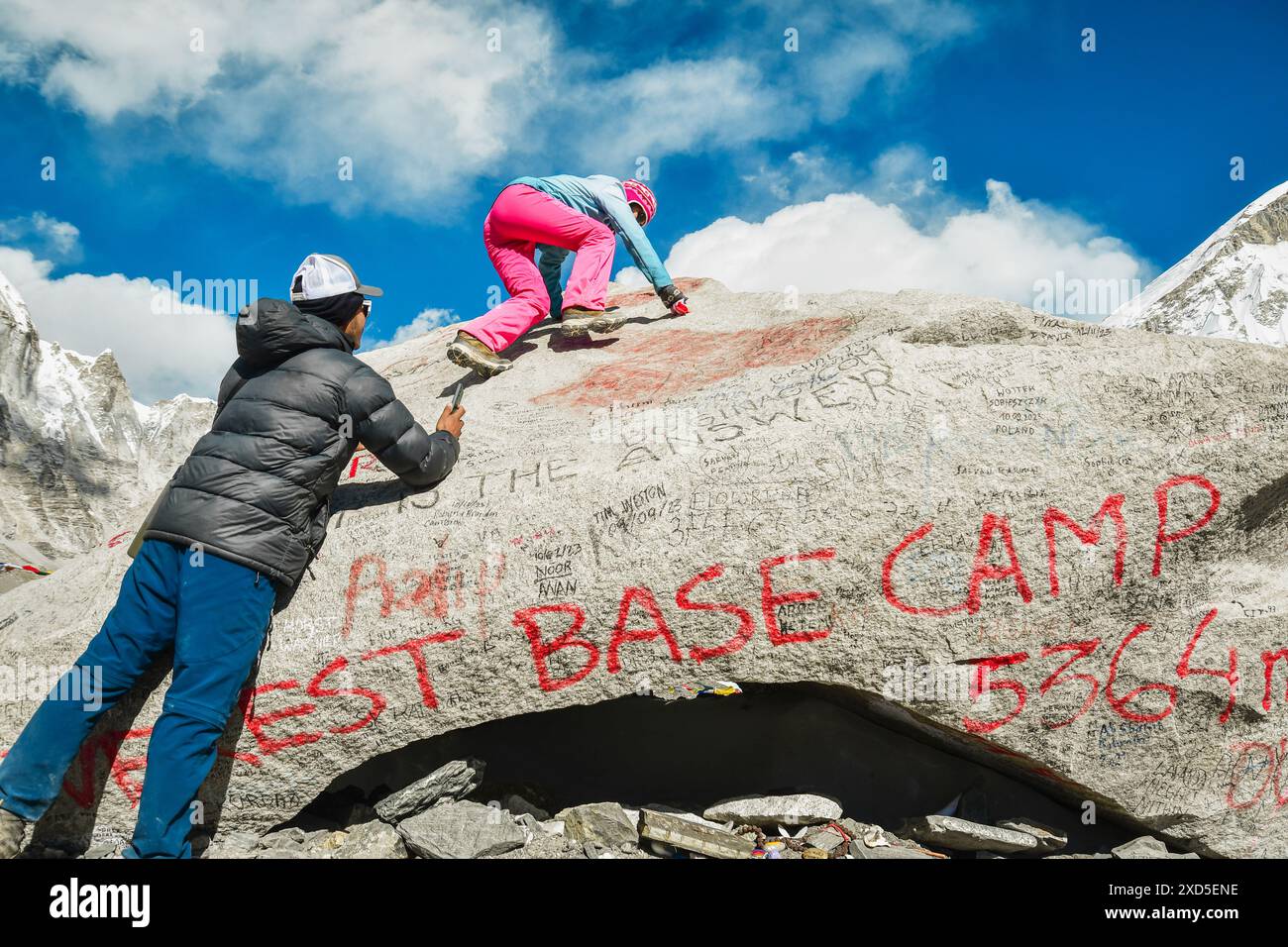 Nepalese male guide helps caucasian trekker to climb famous Everest ...