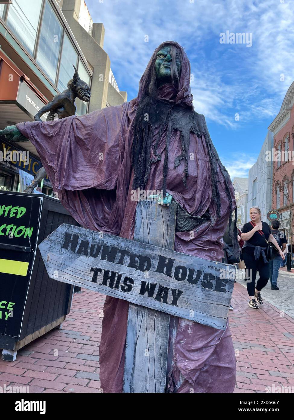 A ghoulish figure points visitors towards a haunted house attraction ...