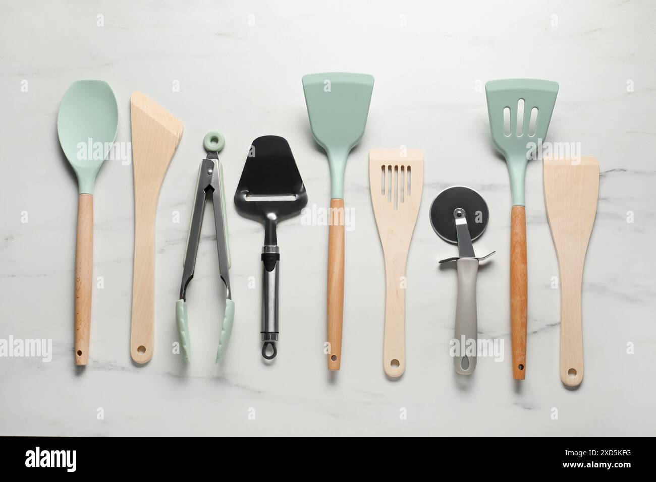 Different spatulas and other kitchen utensils on white marble table ...