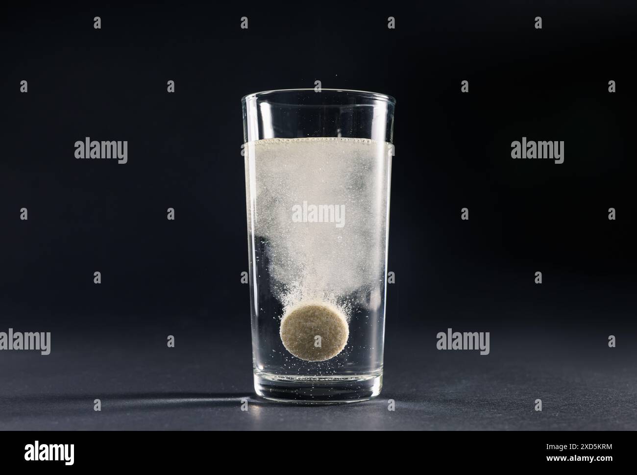 Effervescent pill dissolving in glass of water on grey table Stock ...