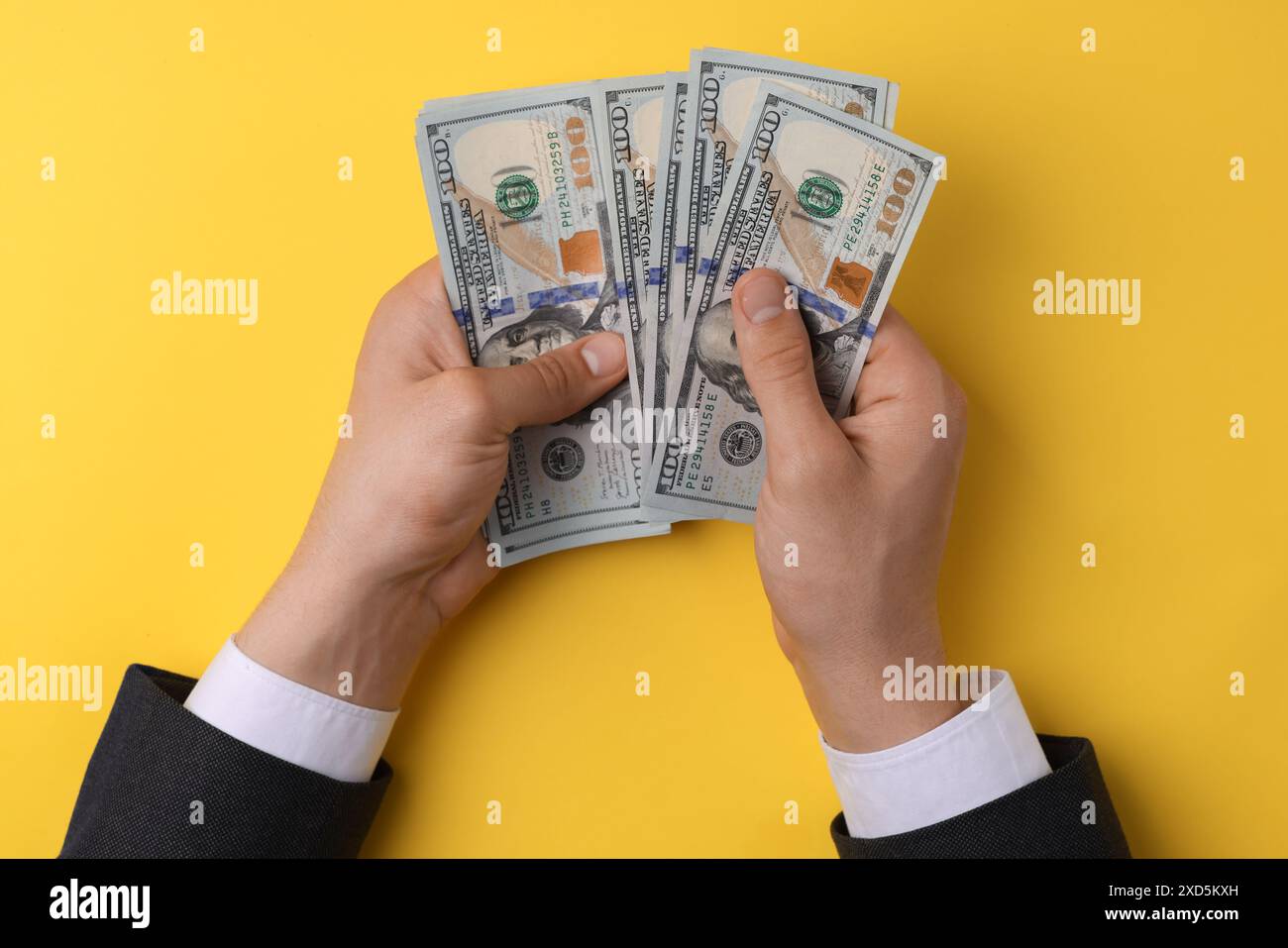 Money exchange. Man holding dollar banknotes on yellow background, top ...