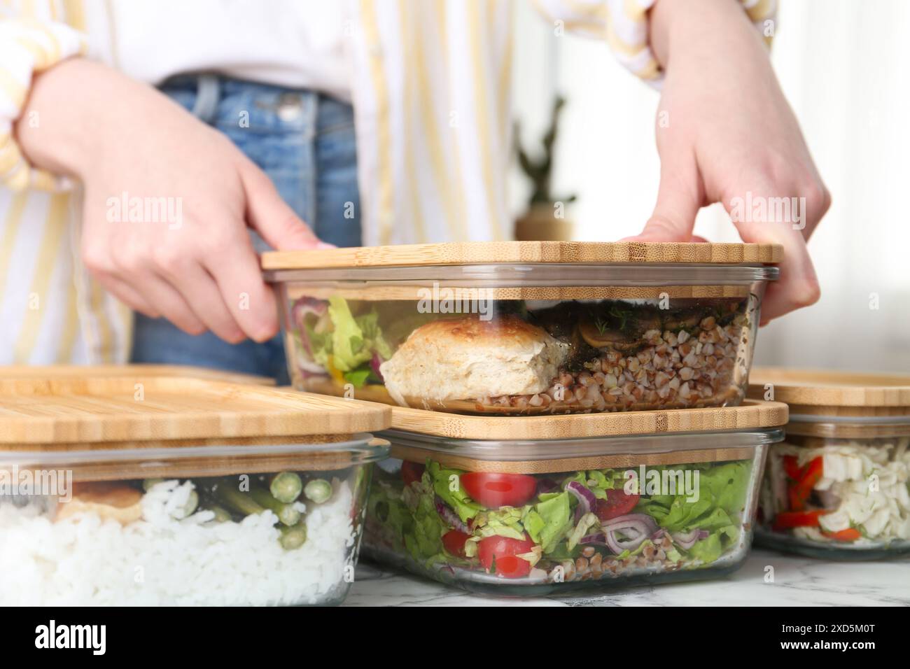 Healthy food. Woman closing glass container with meal at white marble ...