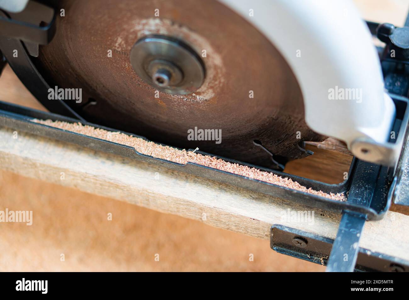 Close-up of a circular saw cutting through a piece of wood, with ...
