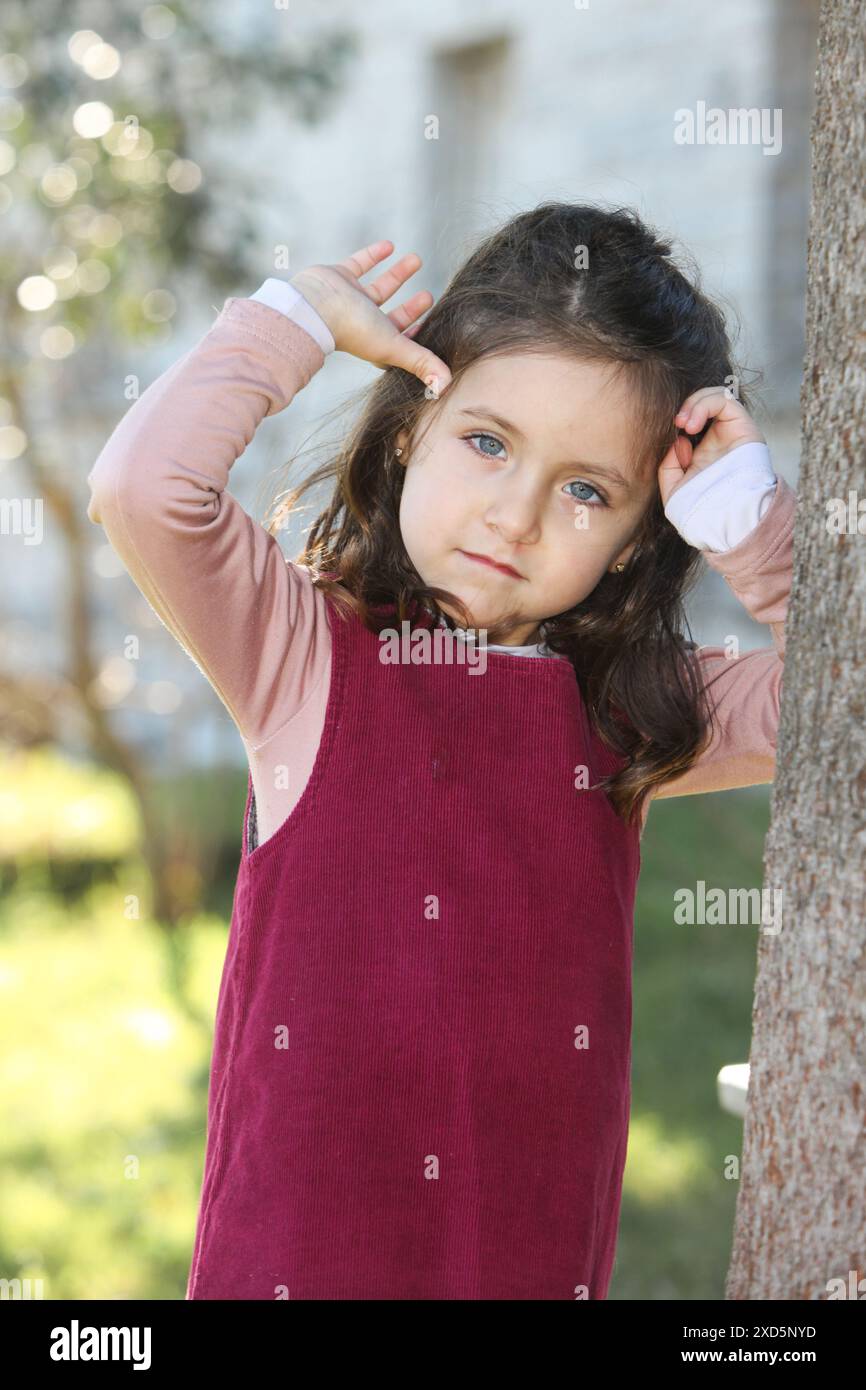 portrait of a serious beautiful little girl next to the tree in the ...