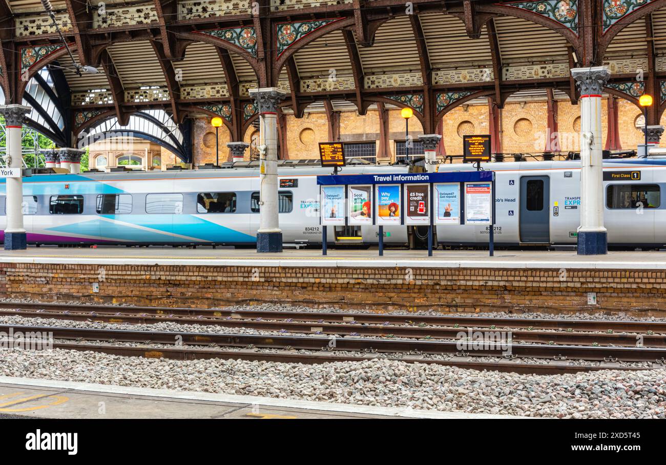 A modern train stands at a historic railway station platform under a ...
