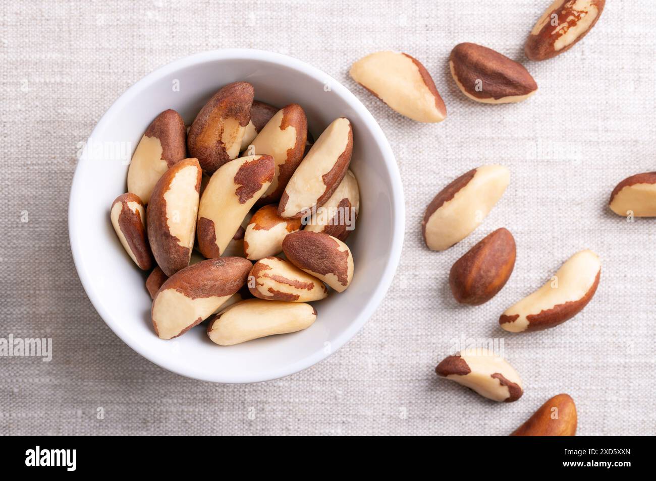 Brazil nuts in a white bowl on linen fabric. Dried seeds of ...