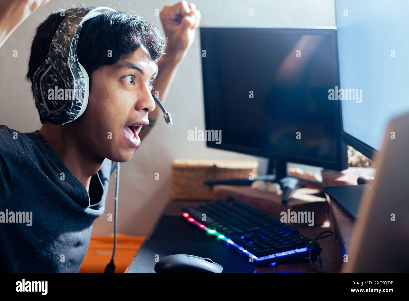 A young man wearing a headset is excitedly cheering while looking at a ...