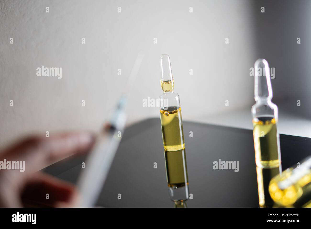 Close-up of medical ampoules with yellow liquid and a syringe on a ...