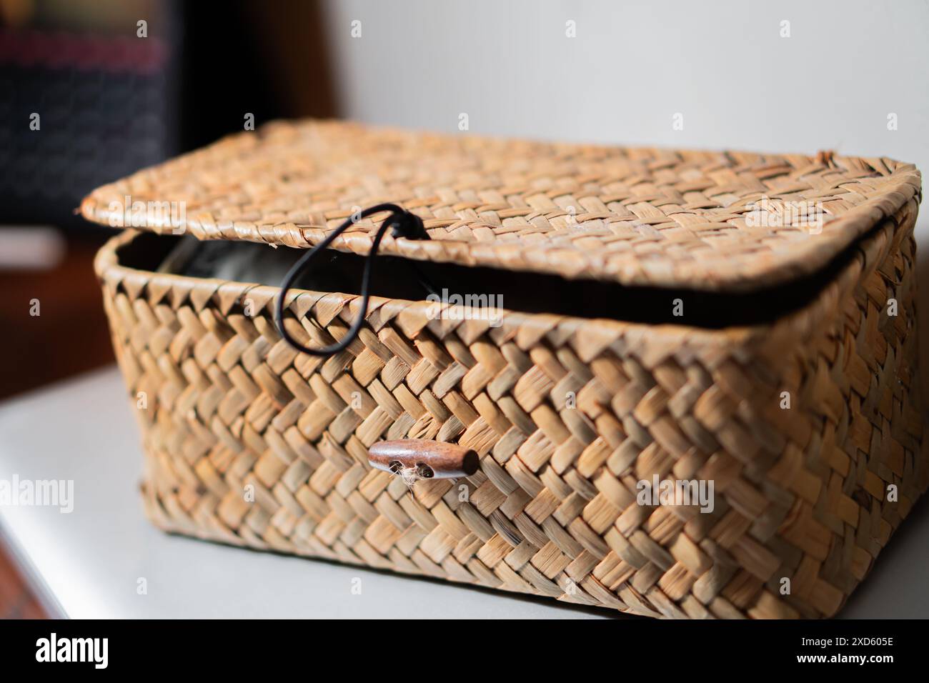 A close-up of a woven wicker basket with a partially open lid ...