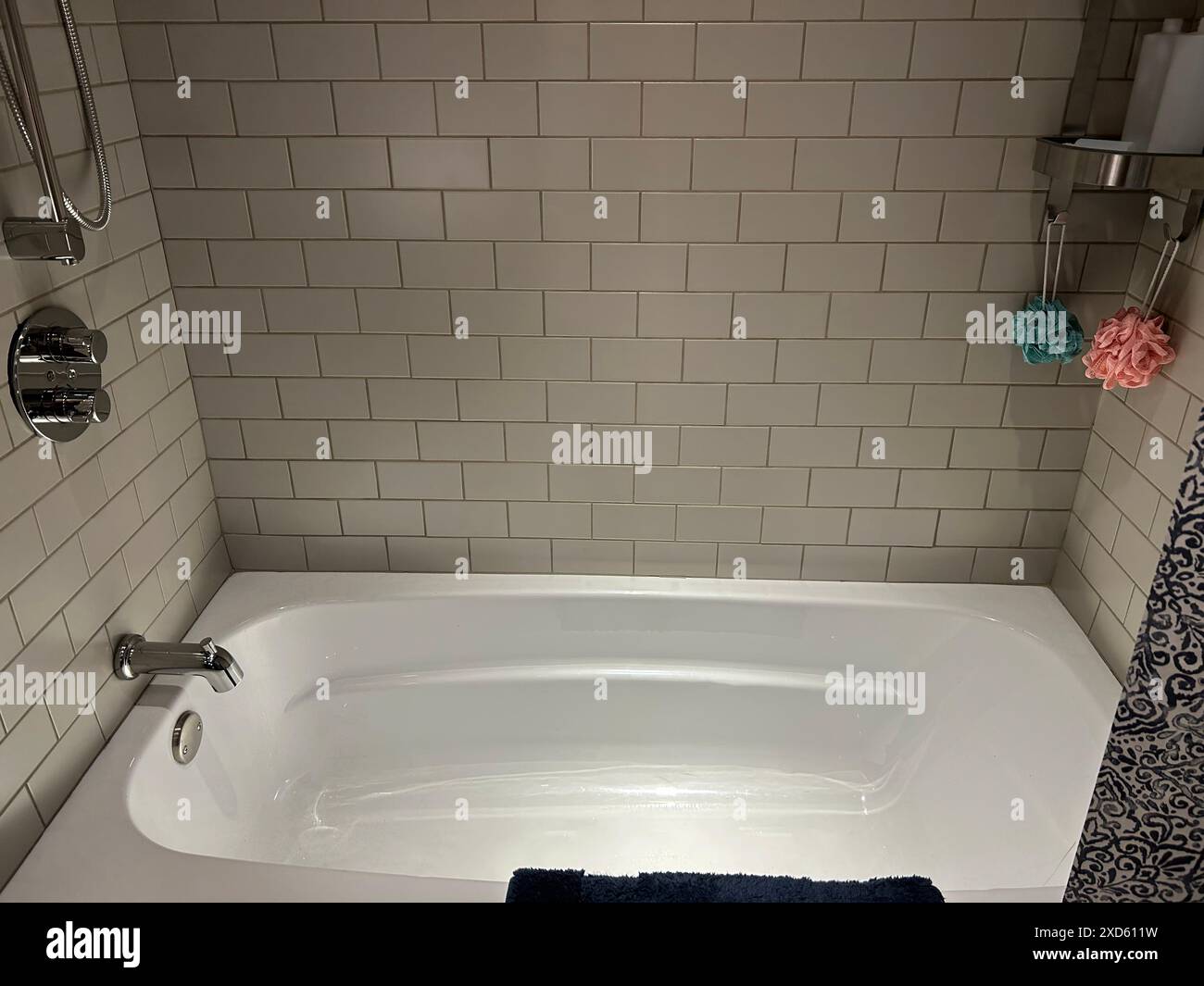 A modern bathroom features a white bathtub with chrome fixtures, white ...