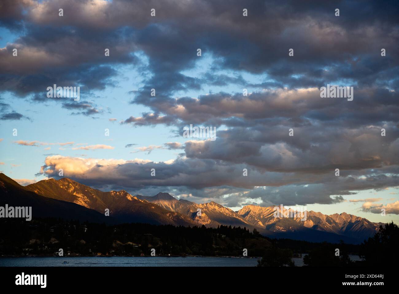 A sunrise illuminates the clouds and the Purcell Mountains over Lake ...