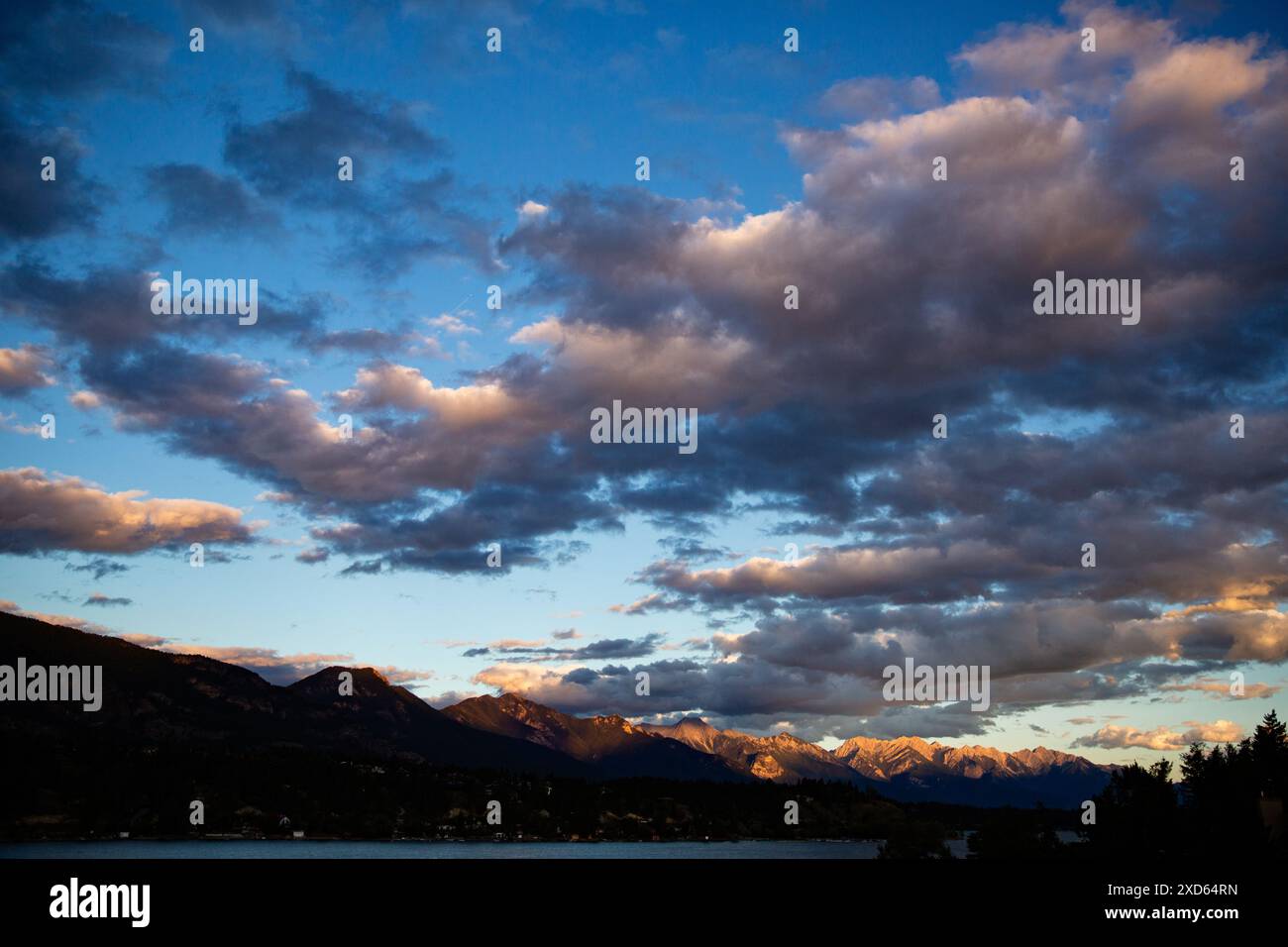 A sunrise illuminates the clouds and the Purcell Mountains over Lake ...