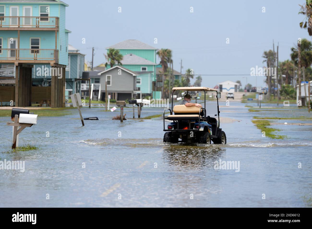 Jamie Baumgart drives his golf cart through water from a tidal surge in ...