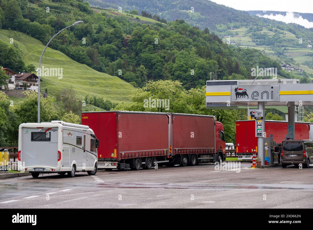 Vehicles, including a camper and trucks, refueling at an ENI gas ...