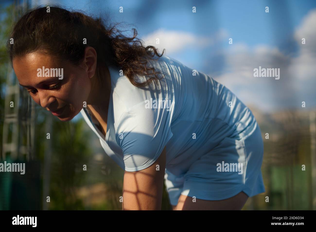 A woman in blue sportswear working out outdoors under sunny weather ...