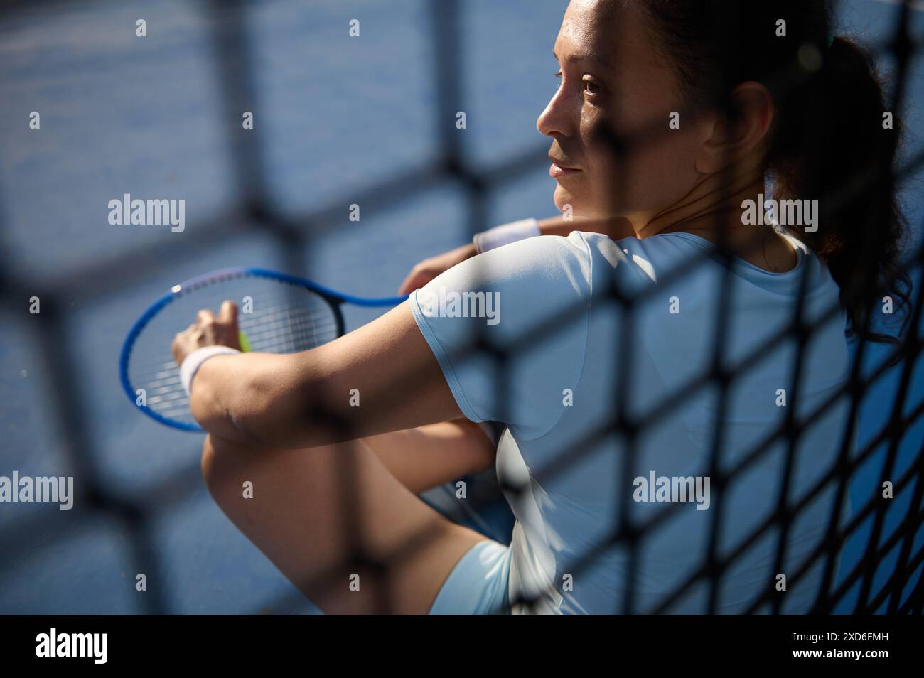 A young female tennis player taking a break on the tennis court ...