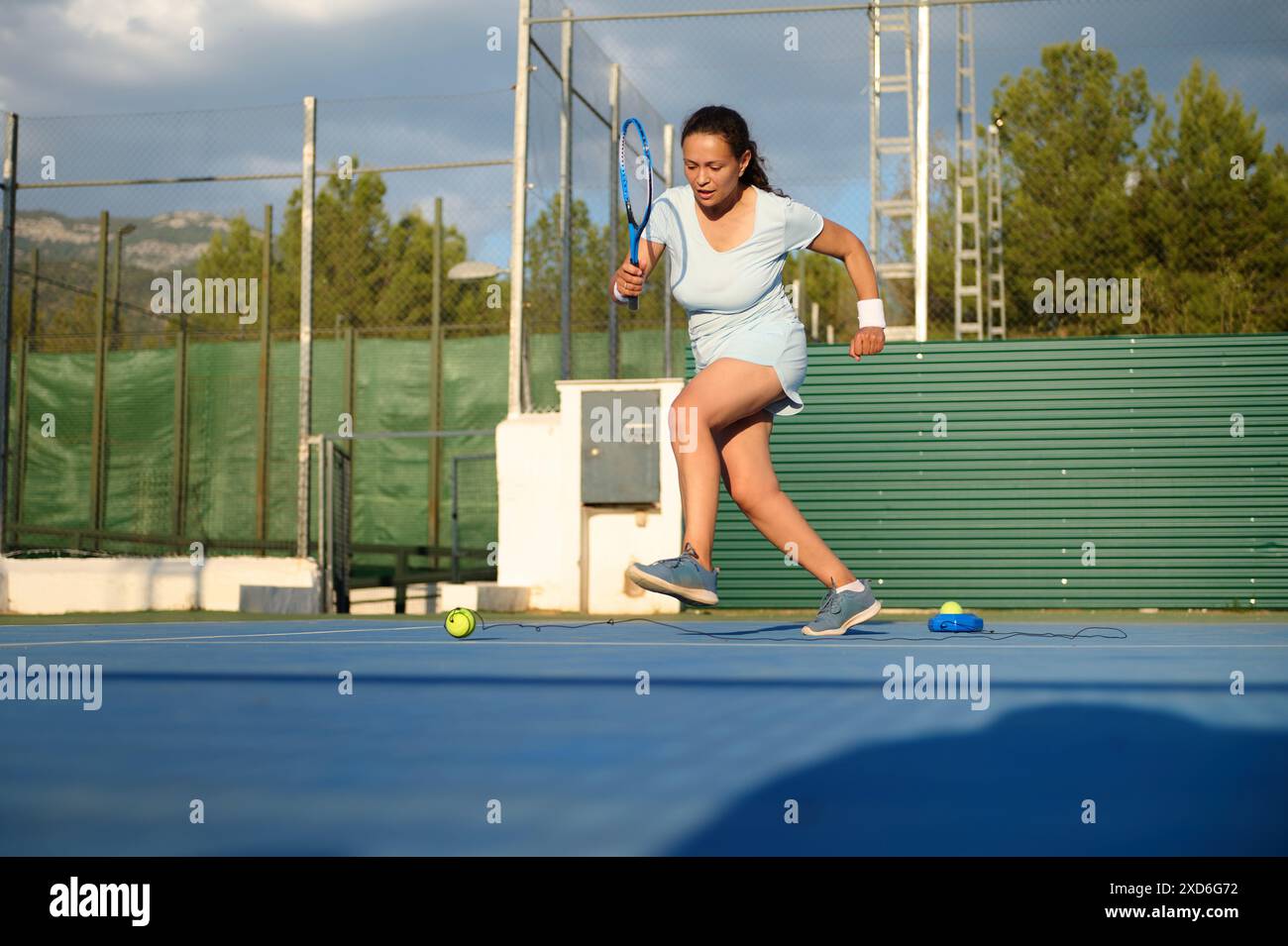Female tennis player in action, practicing on an outdoor court ...