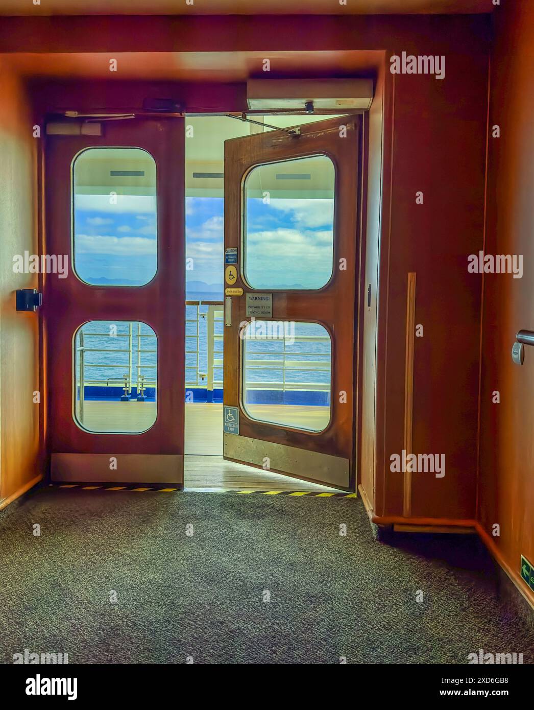 Open doors on cruise ship corridor lead to outside view of ocean, deck ...