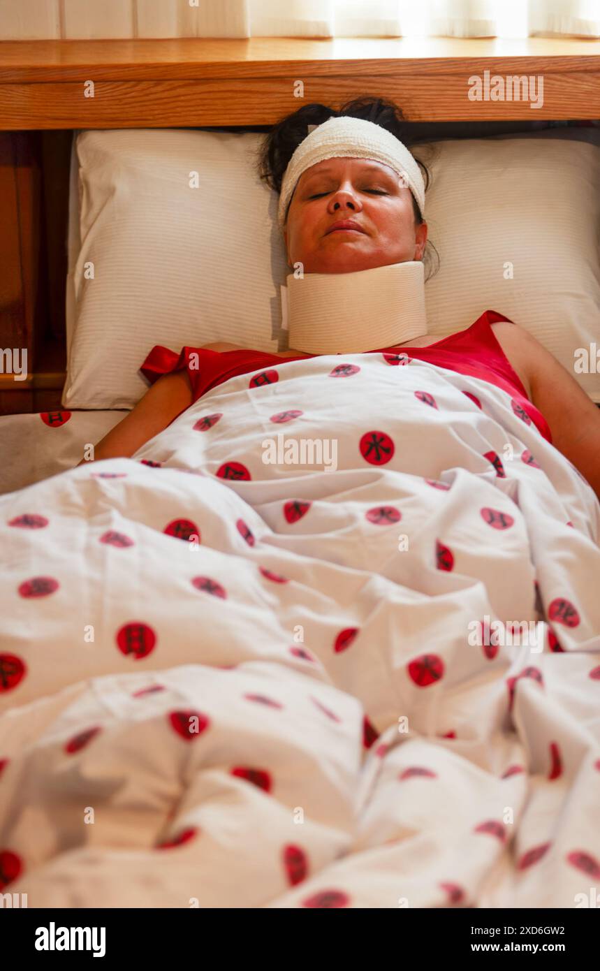 sick woman wearing a neck collar and a head bandage in the bed ...