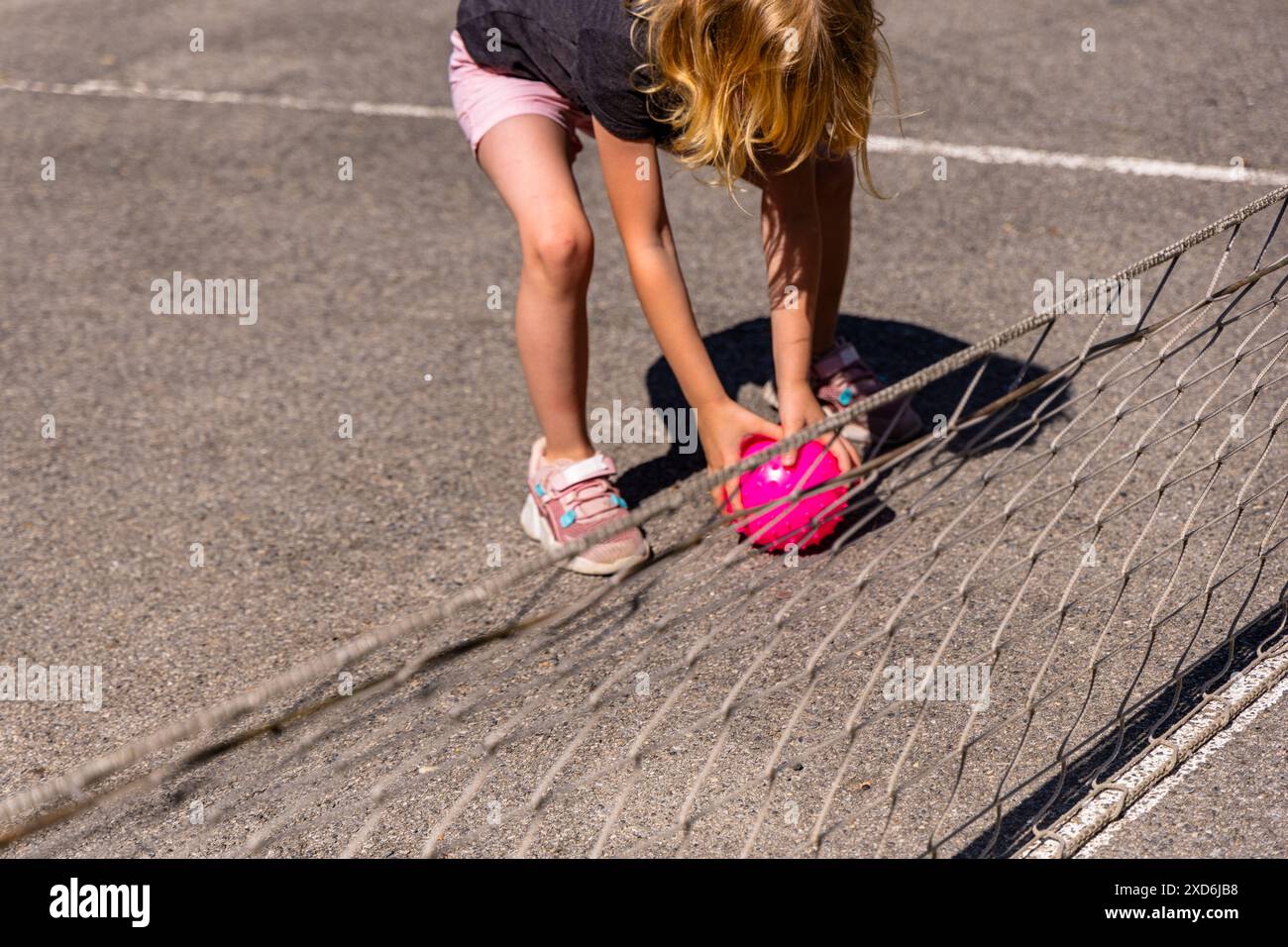 Young Girl Reaching for Pink Ball on Outdoor Court Stock Photo - Alamy