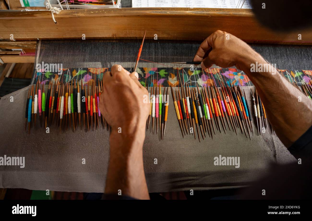 A Kashmiri artisan is using wooden needles and Pashmina yarn to weave a ...