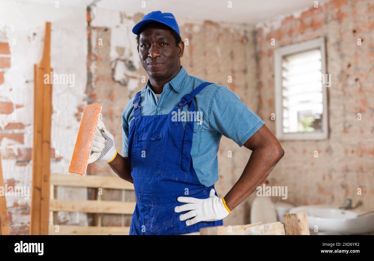 Professional plasterer standing with sponge float in building under ...