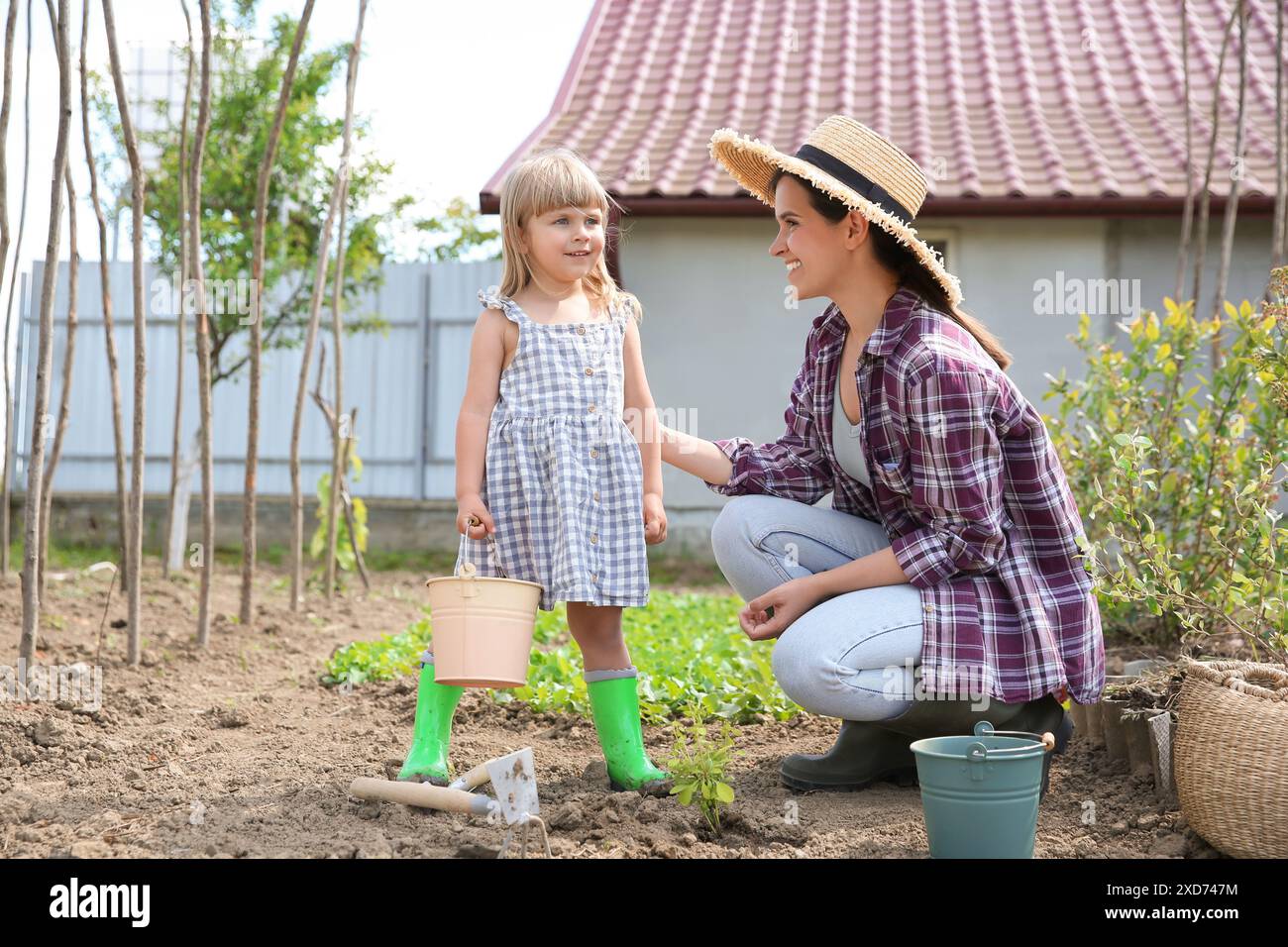 Mother and her cute daughter planting tree together in garden Stock ...