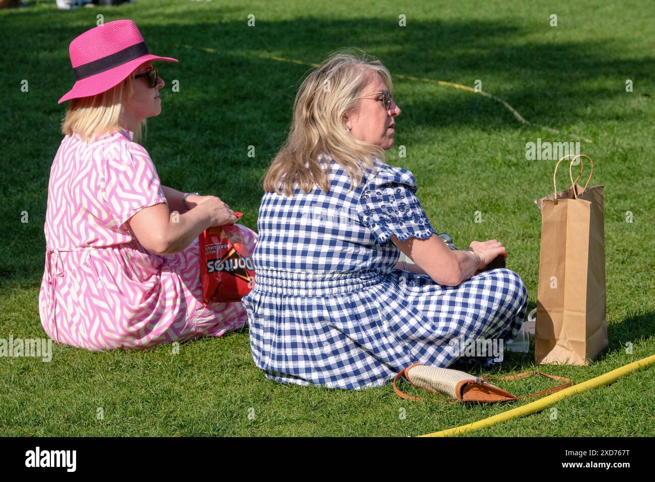 London, UK. Two women enjoy the sunny weather as they sit down in ...