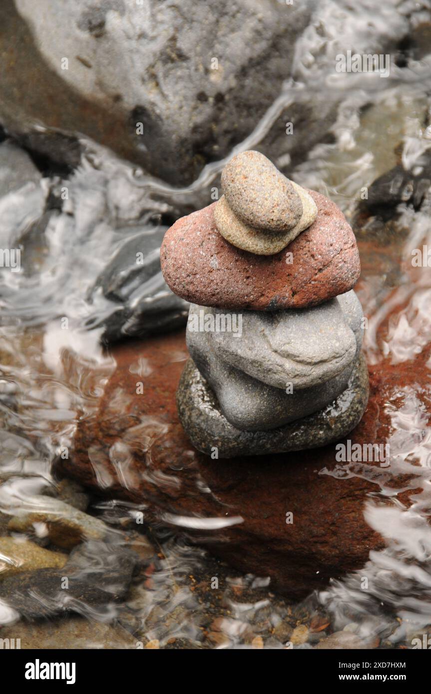 A small colorful rock cairn balancing in a stream Stock Photo - Alamy