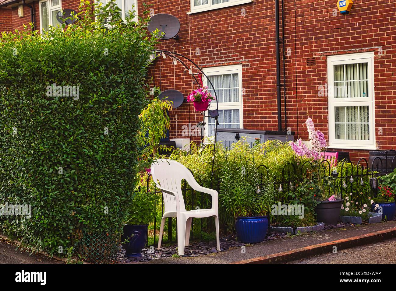 A small, well-maintained garden in front of a brick house. The garden ...