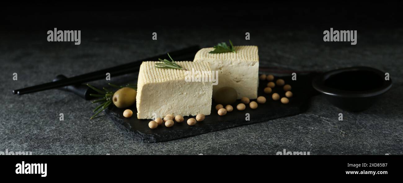 Delicious tofu with beans, soy sauce and olives on grey table, banner ...