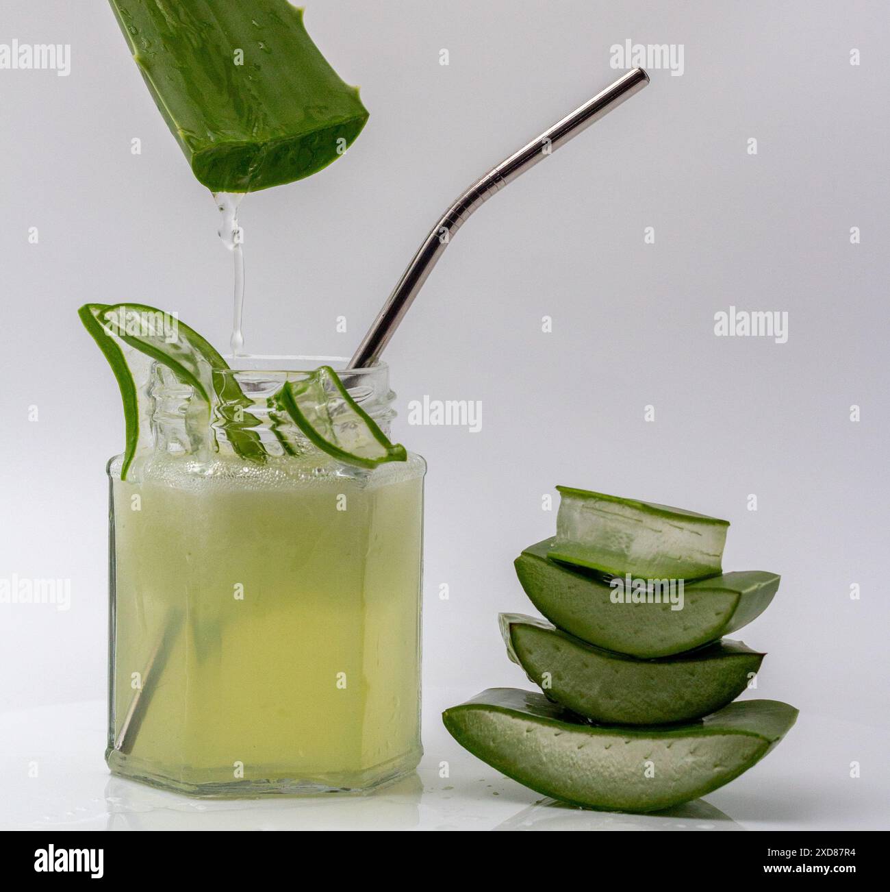 Aloe vera gel dripping on a jar of aloe vera juice with sliced and ...