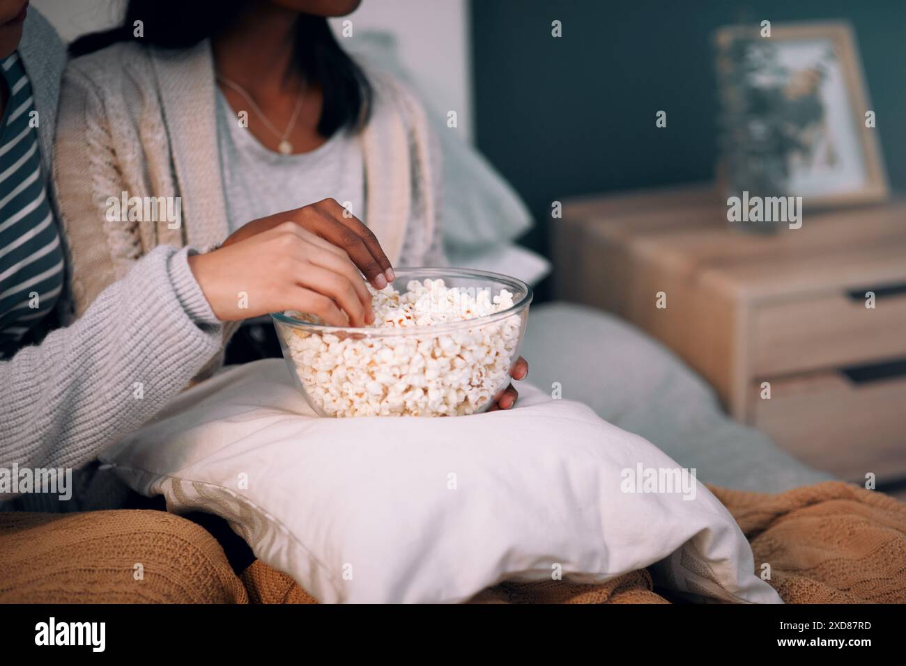 Hands, women and home in bed with popcorn snack for social visit, bonding and sleepover. People ...