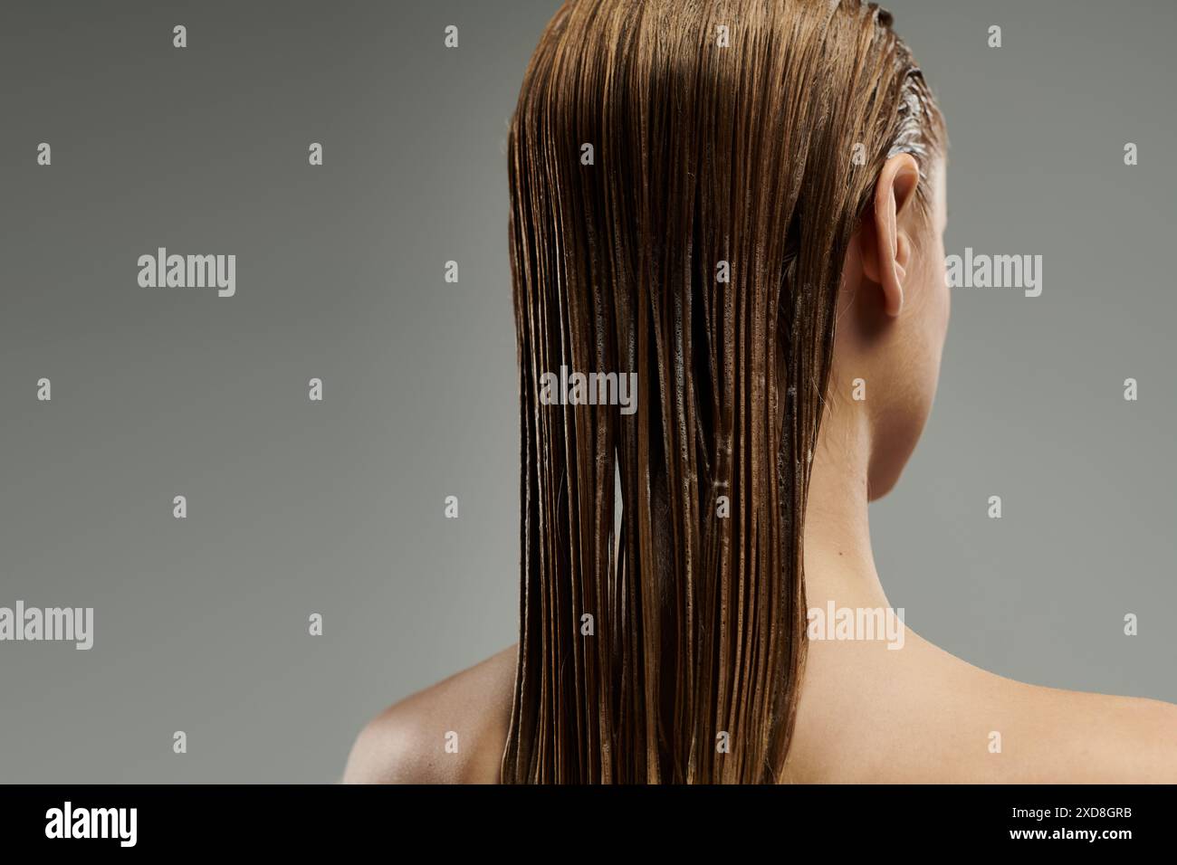 A young woman showcases her hair care routine with wet, flowing locks ...