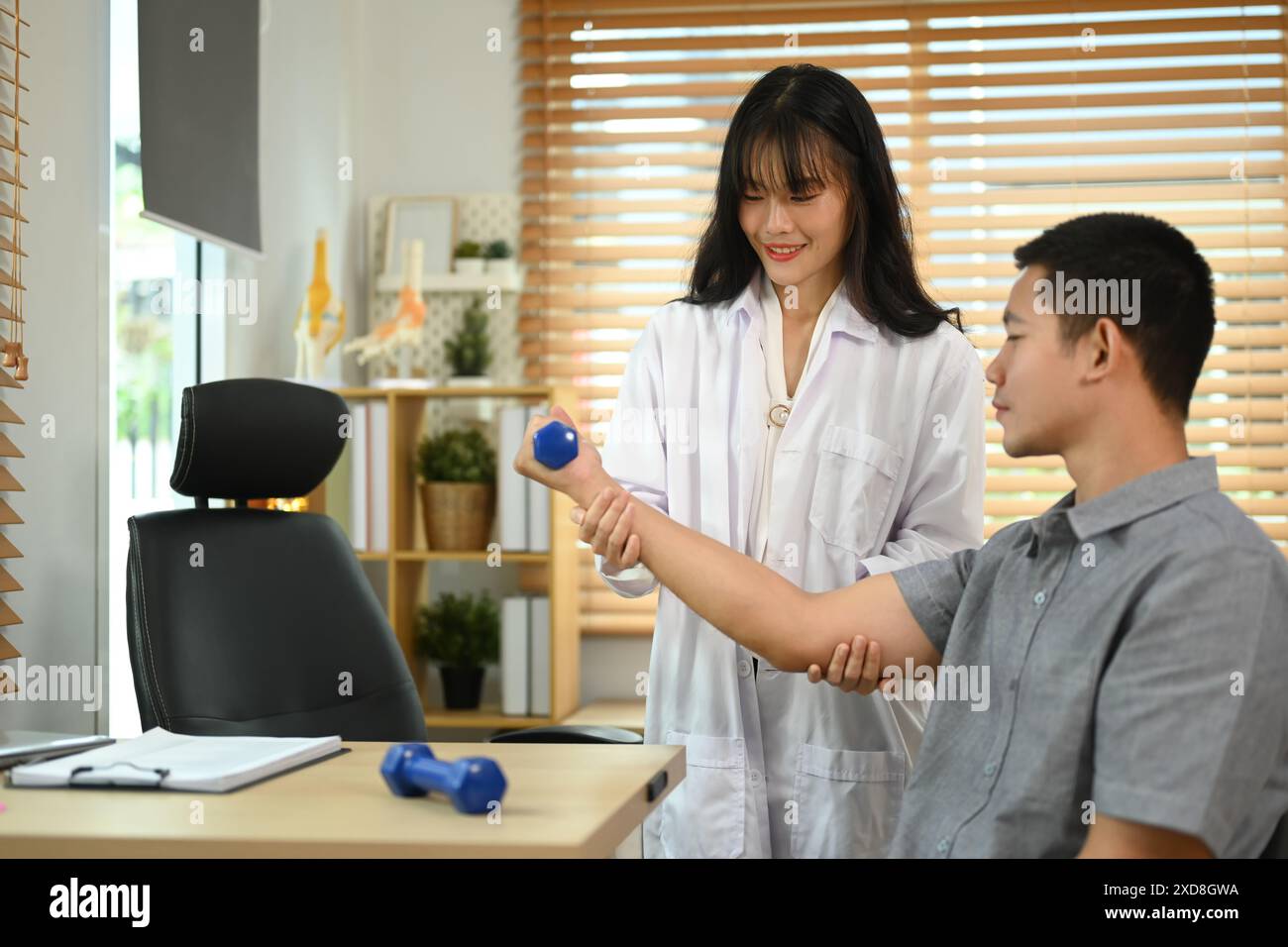 Asian male patient patient lifting light weight dumbbells under ...