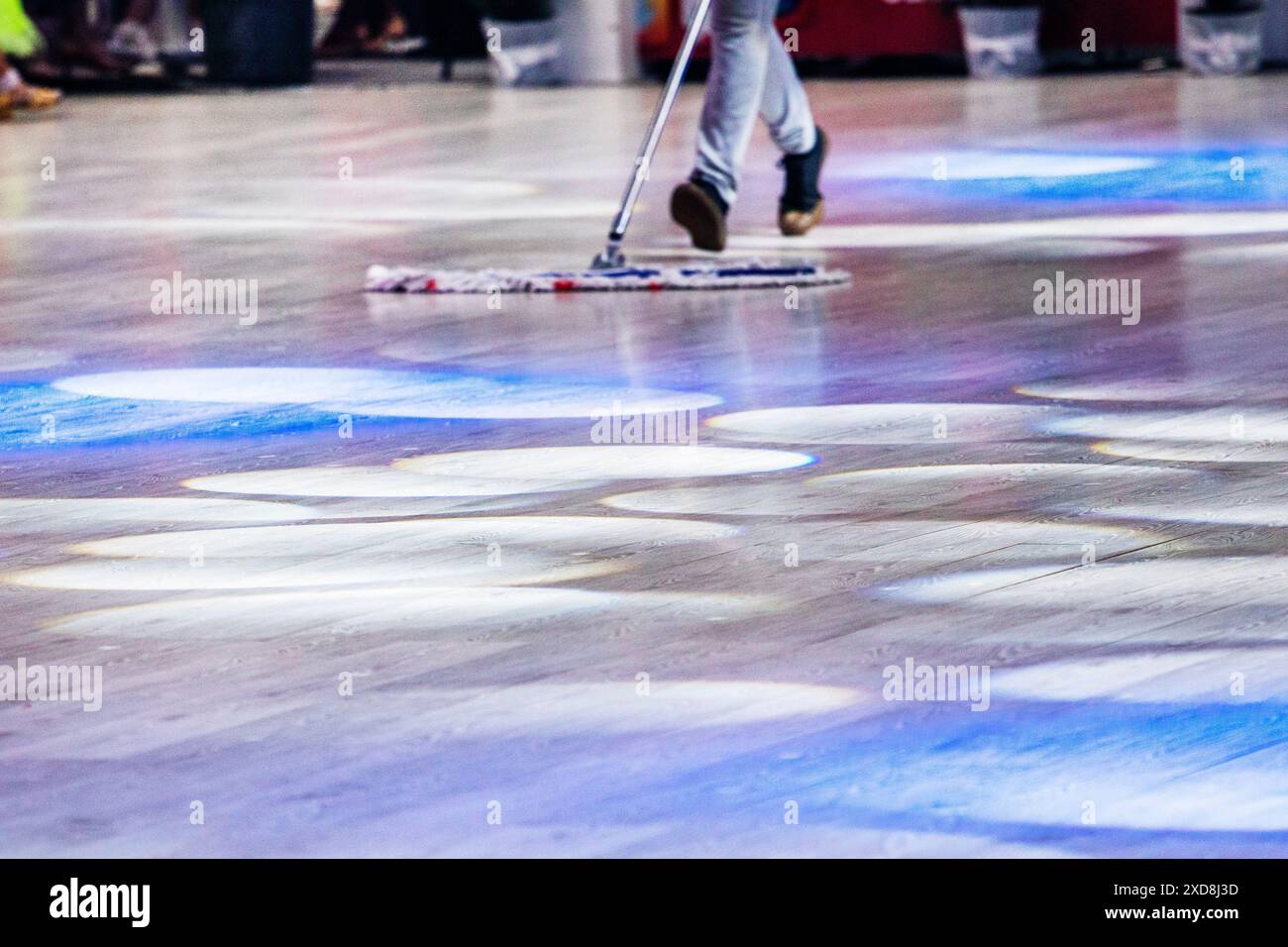 wipe the parquet floor with a mop and rag before a dance competition ...