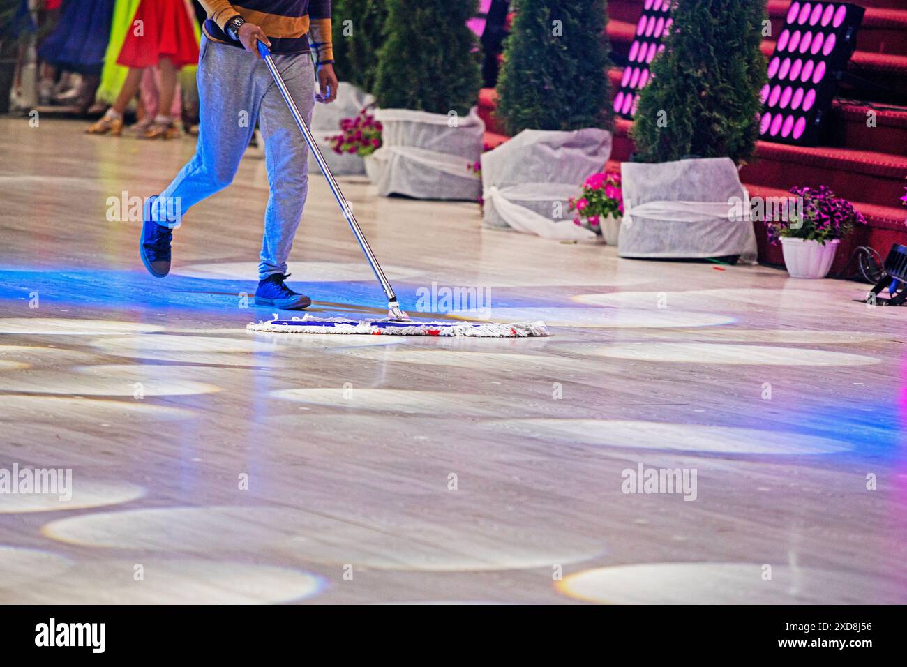 Wipe the parquet floor with a mop and rag before a dance competition ...