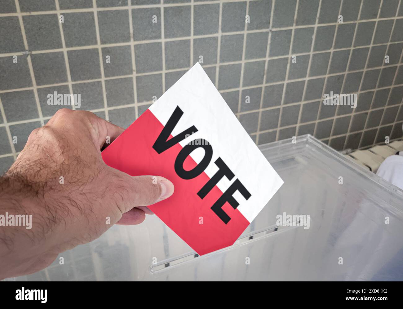 A close-up photograph captures a hand placing a voting ballot with the ...