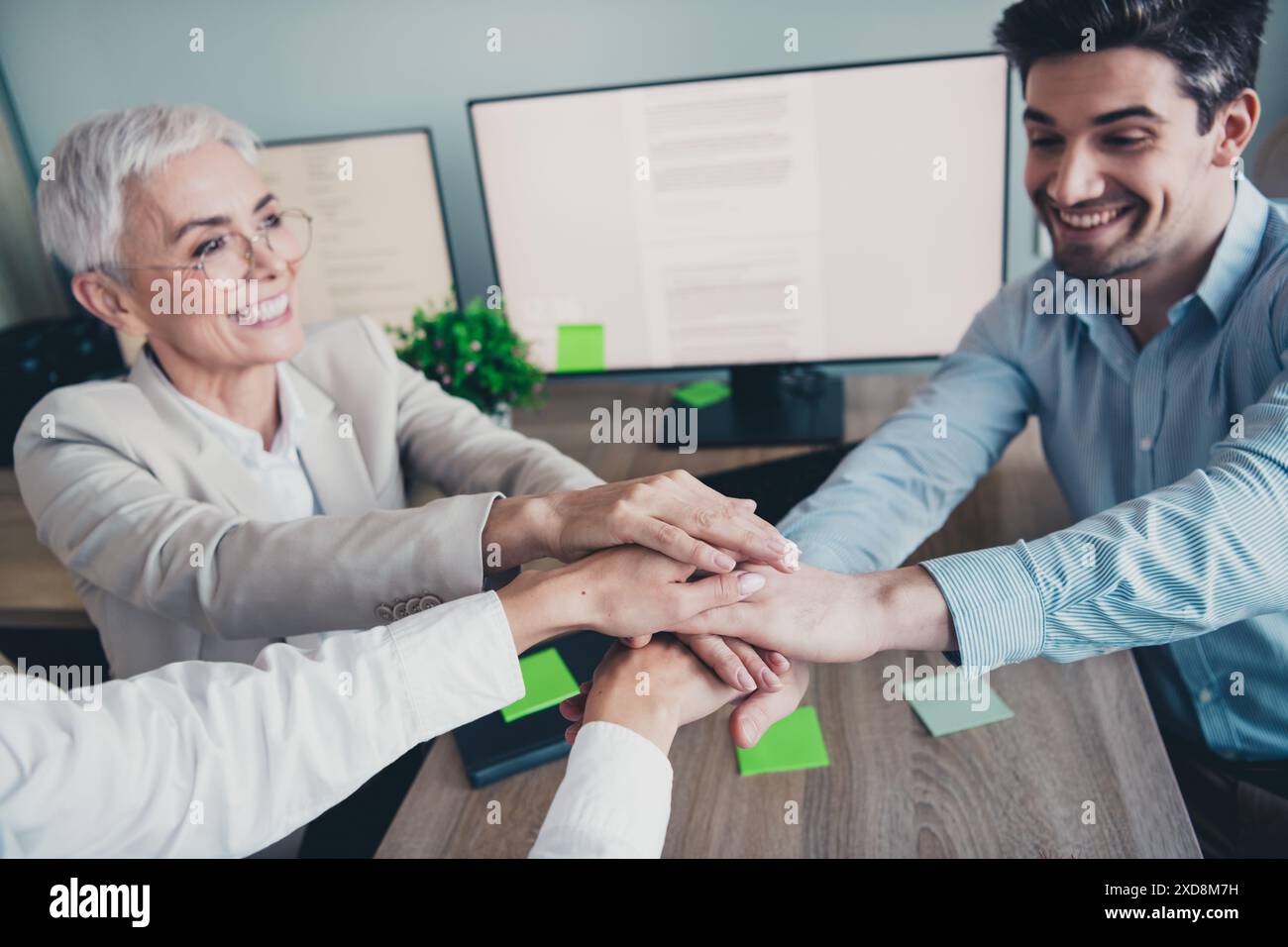 Photo of business people put hands together doing teambuilding training ...