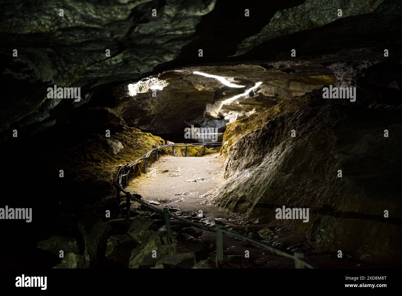 Dark Cave Entrance With Path Leading To Light Stock Photo - Alamy