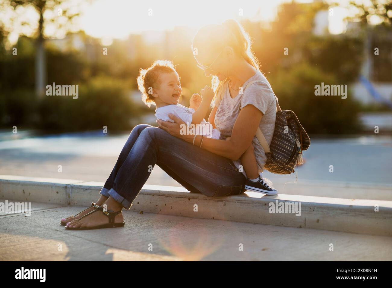 A mother and her baby boy bond while sitting on a concrete ledge in the ...