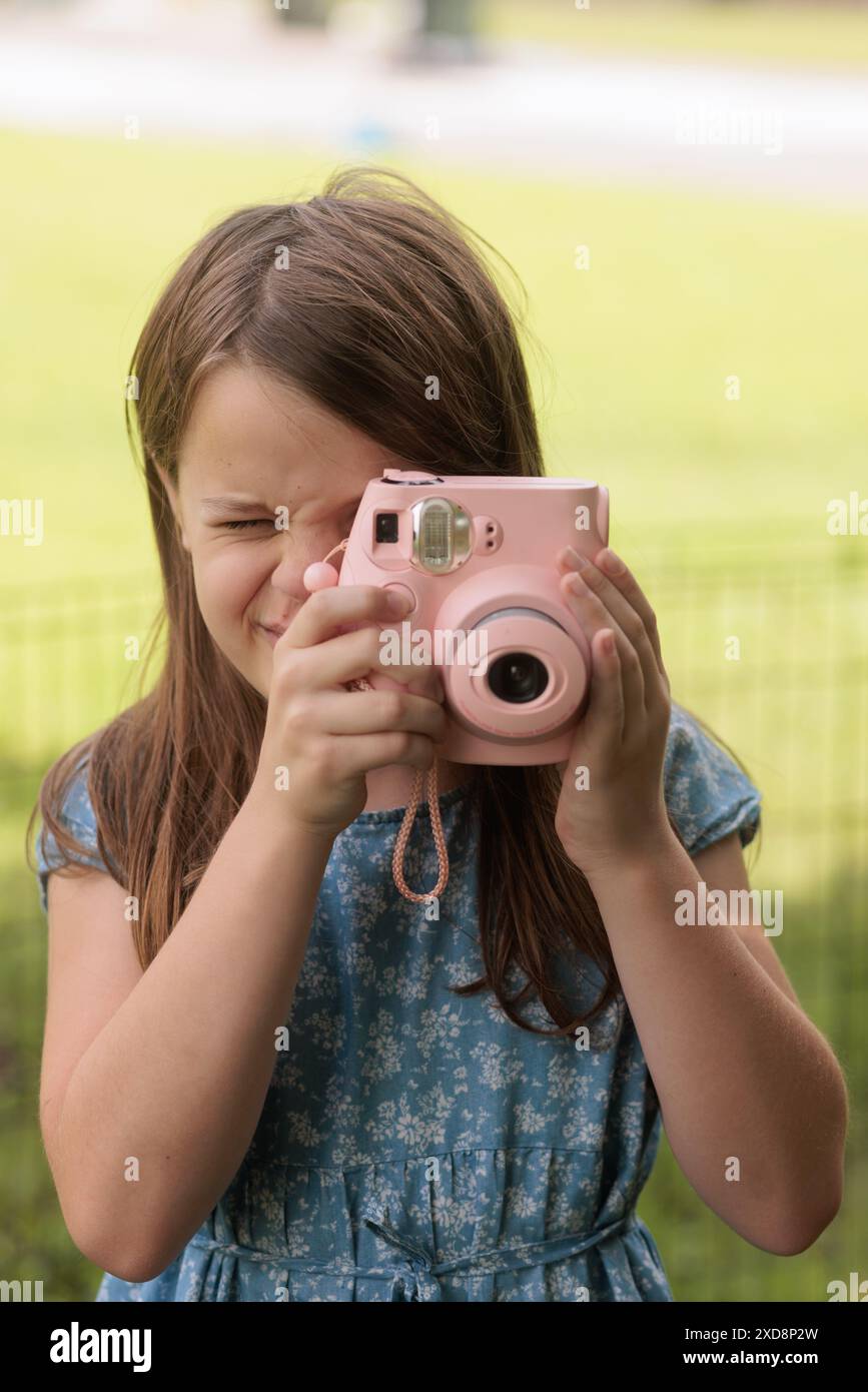 A young girl taking a photo with a pink camera outdoors Stock Photo - Alamy
