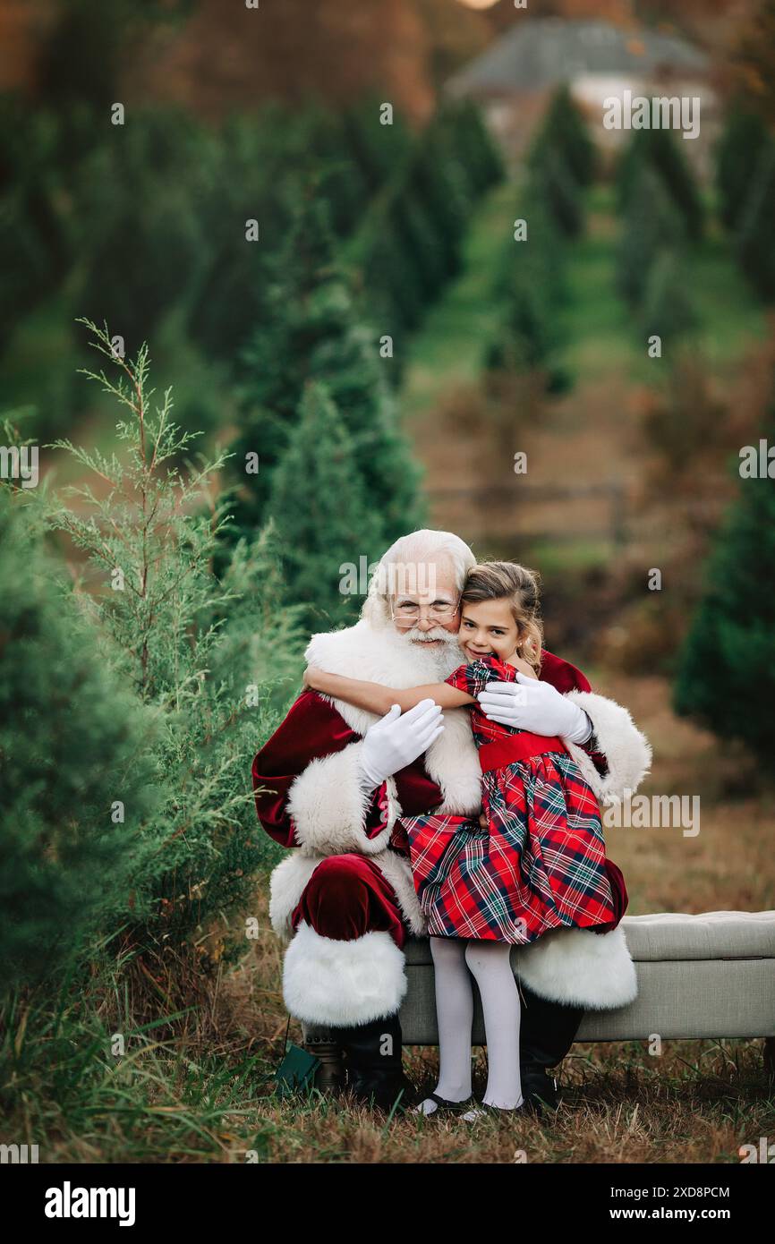 Santa hugging a girl in a plaid dress at a Christmas tree farm Stock ...