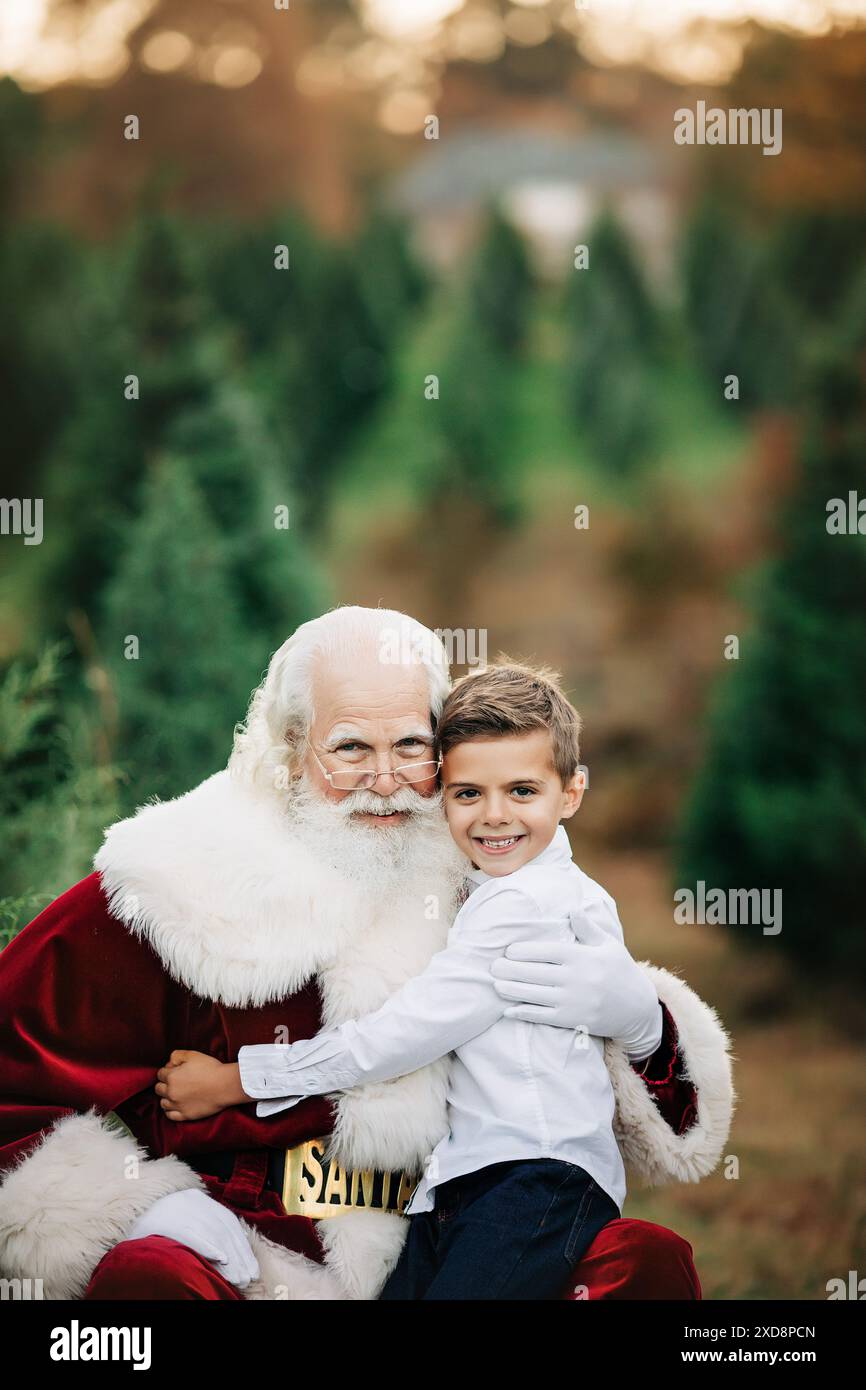 Santa hugging a boy in a white shirt at a Christmas tree farm Stock ...