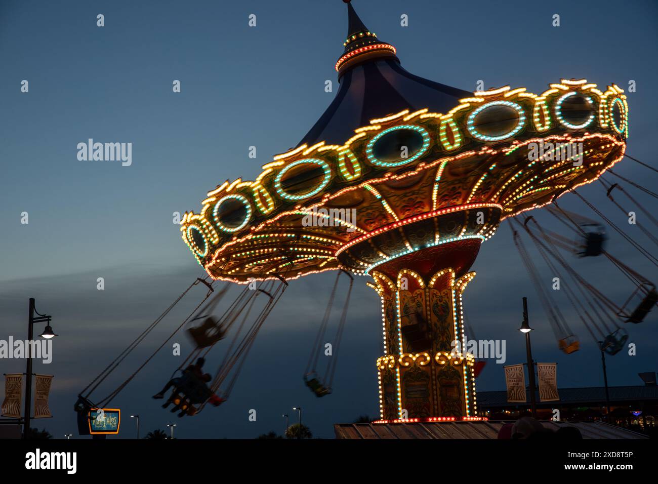 Lit carousel swing ride in motion at duskar evening sky Stock Photo - Alamy