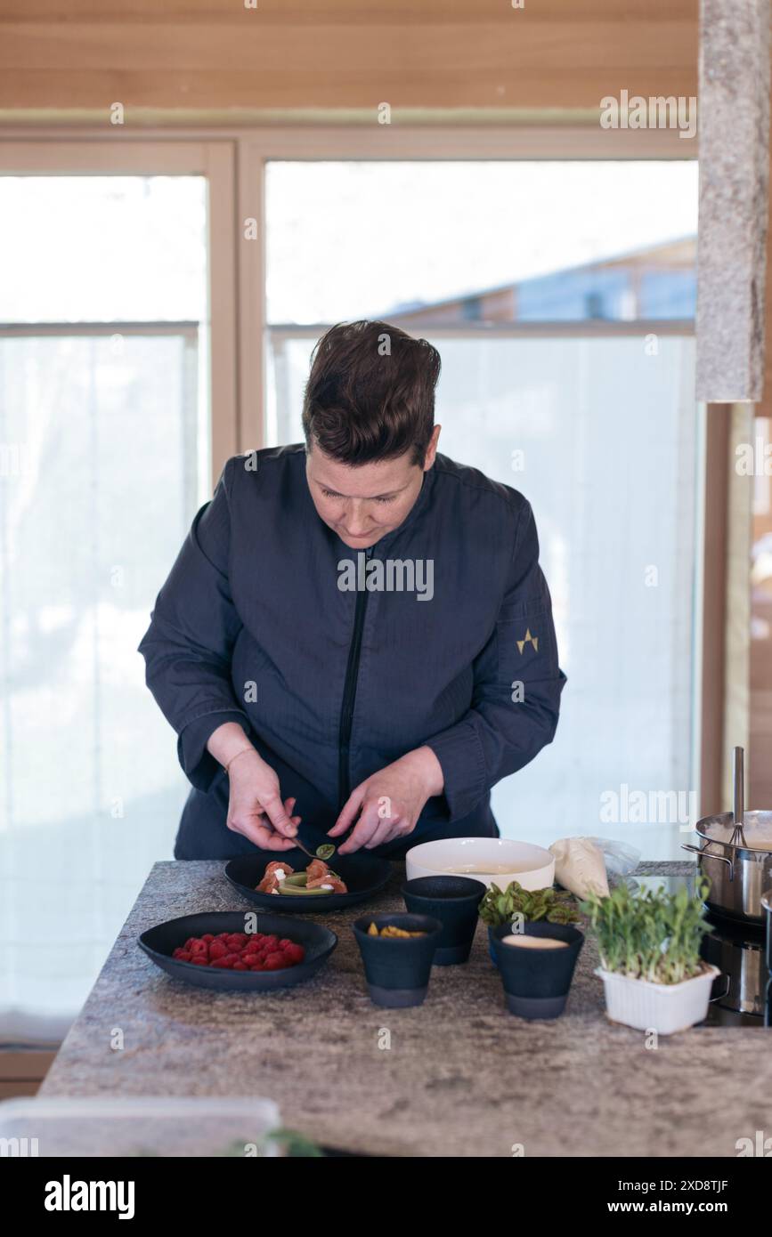 Chef plating food in a modern kitchen with herbs and utensils Stock ...