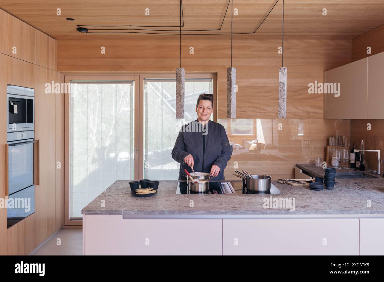 Chef in a modern wooden kitchen with minimalist design Stock Photo - Alamy
