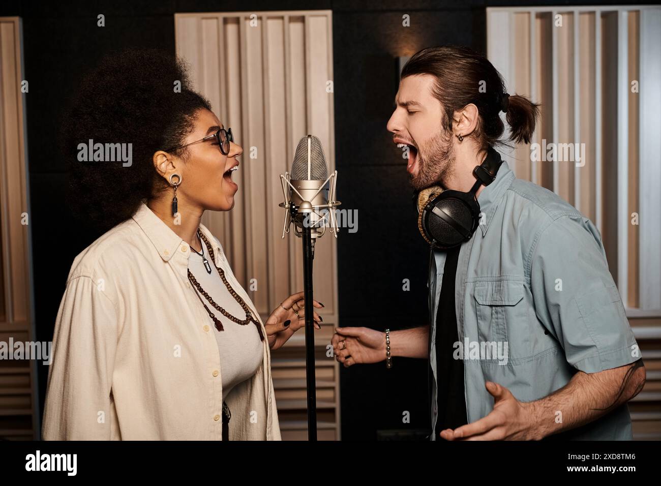 A man and woman passionately singing into a microphone in a recording ...
